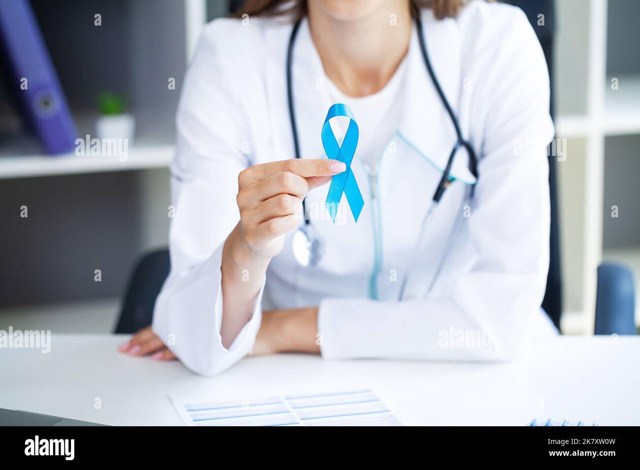 Doctor holding blue awareness ribbon at her office Stock Photo - Alamy