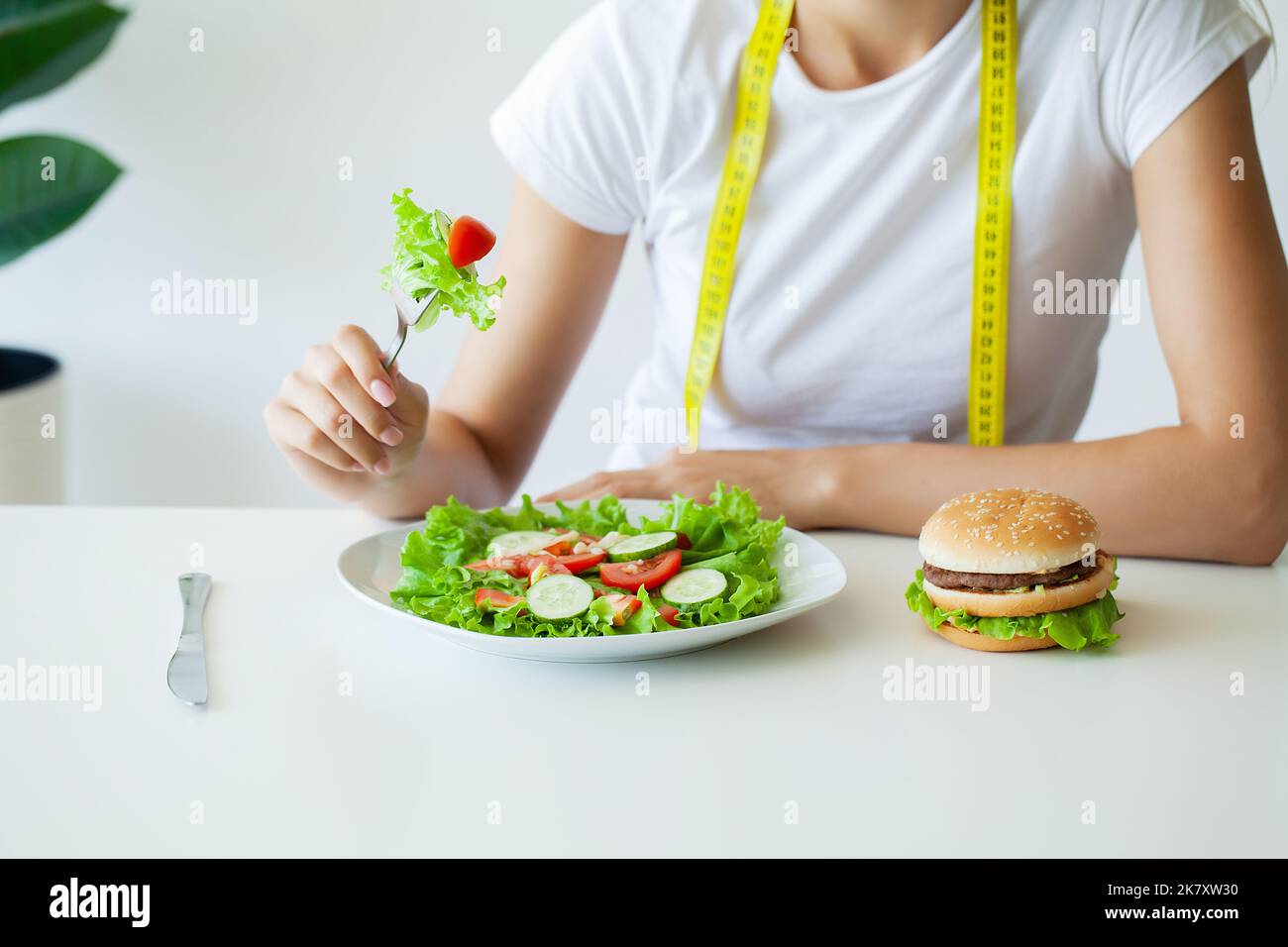 Woman decides eating hamburger or fresh salad in kitchen Stock Photo ...
