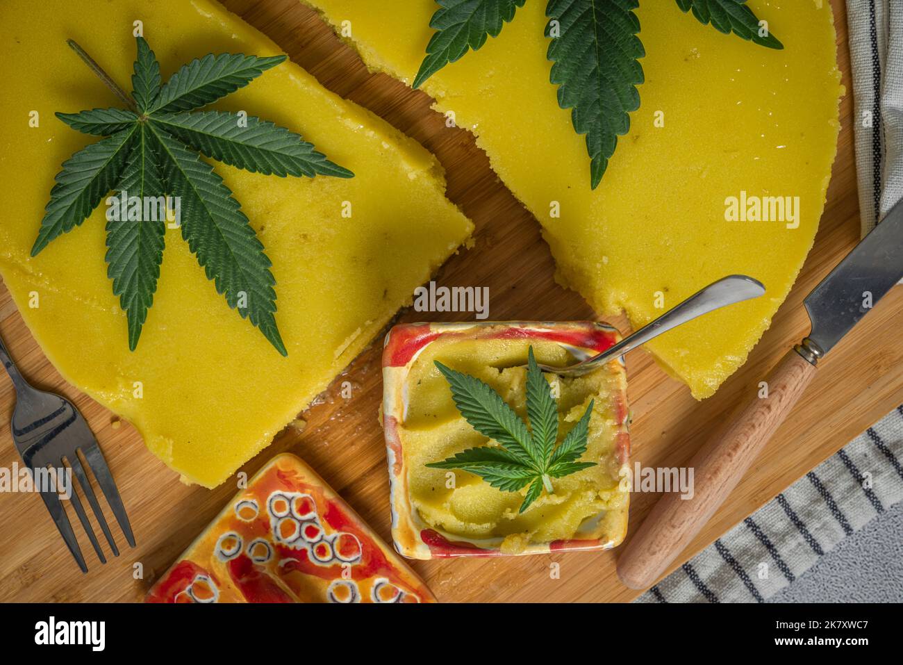Yelllow marijuana butter on light stone table with dish towel and color ...