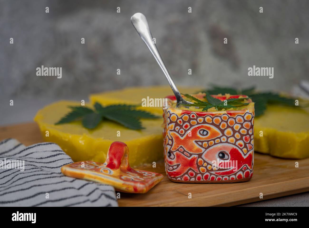 Yelllow marijuana butter on light stone table with dish towel and color ...