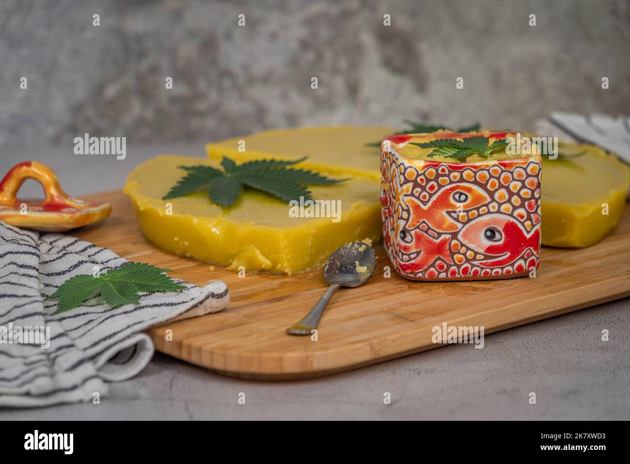 Yelllow marijuana butter on light stone table with dish towel and color ...