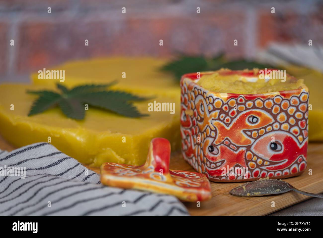 Yelllow marijuana butter on light stone table with dish towel and color ...