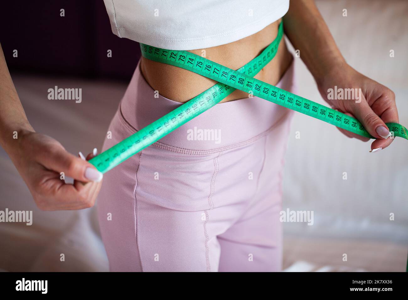 Slim woman measuring her waist with a measure Stock Photo - Alamy