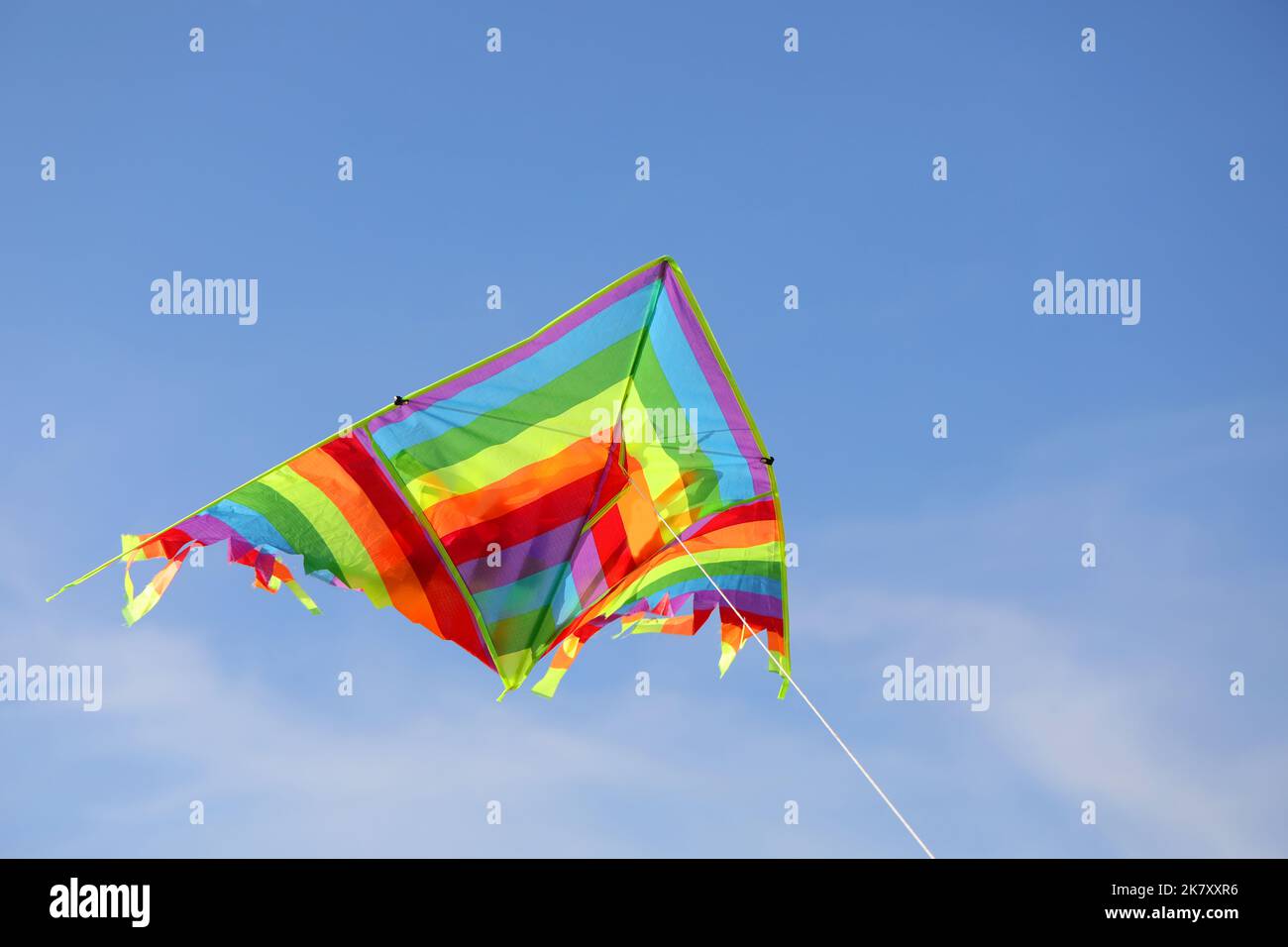 Colorful kite with stripes of various colors of the rainbow flying on ...