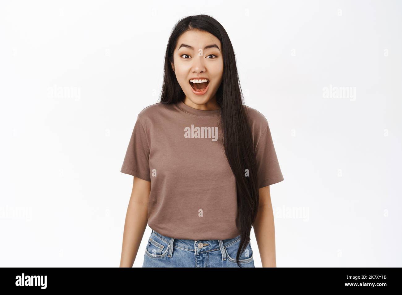 Surprised asian woman gasping, looking amazed at camera, impressed face ...