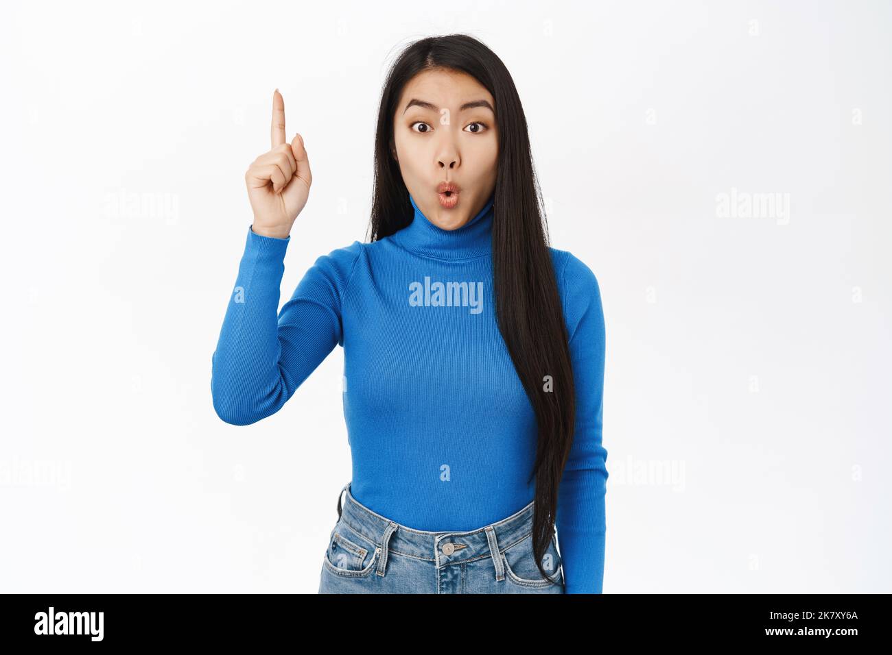 Enthusiastic asian female model pointing finger up, shows advertisement ...