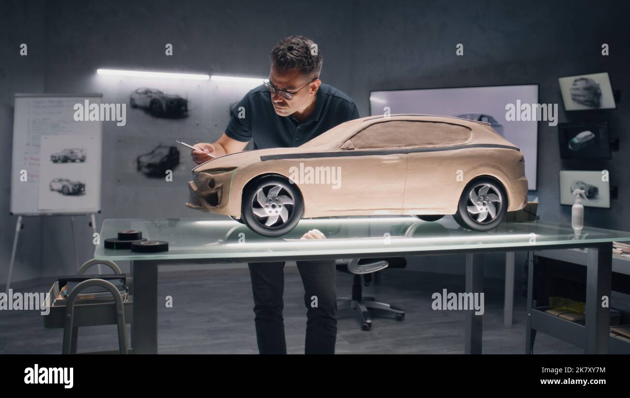 Two male automotive designers working on model of eco friendly electric ...