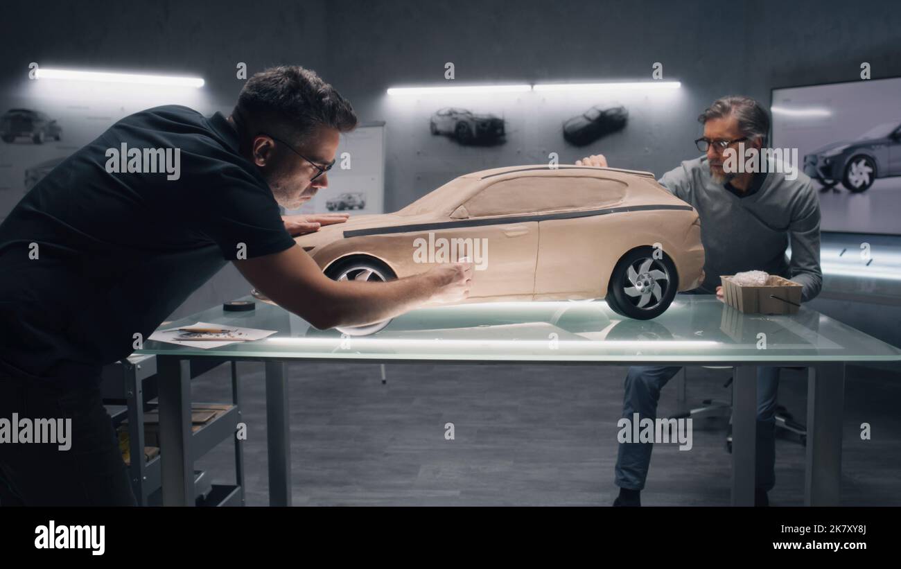 Two male automotive designers working on eco friendly plasticine clay ...