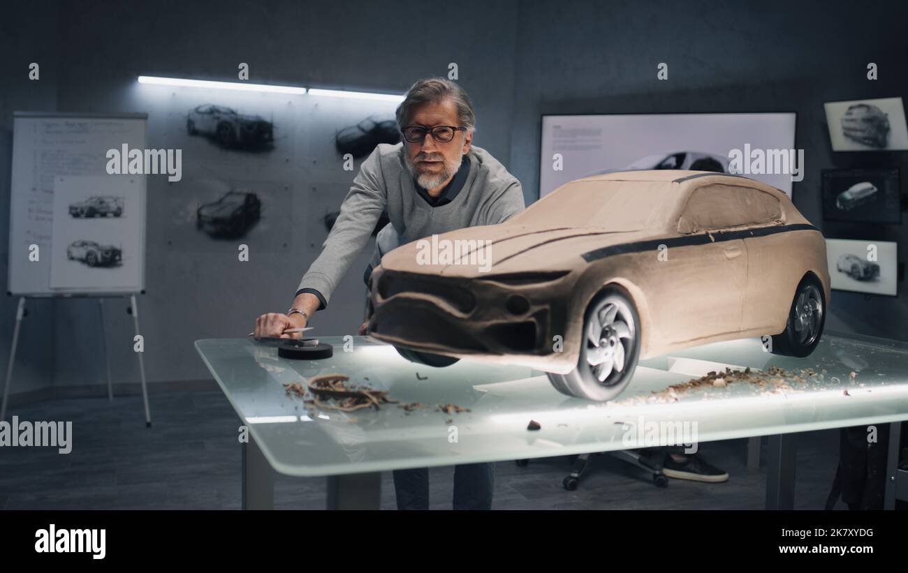 Mature male automotive designer standing near futuristic car model from ...
