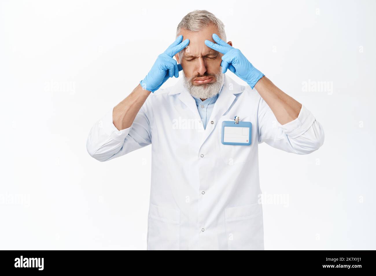 Tired senior male doctor, holding hands on head, migraine, distressed ...