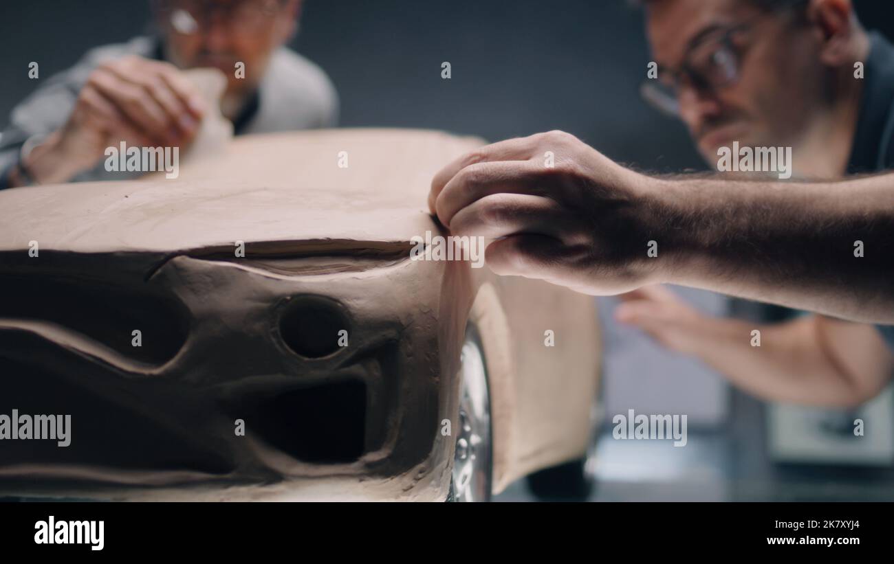 Two male automotive designers creating futuristic plasticine clay ...