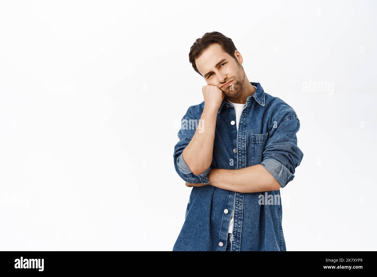 Bored handsome man, looking unamused, staring at camera and sulking ...