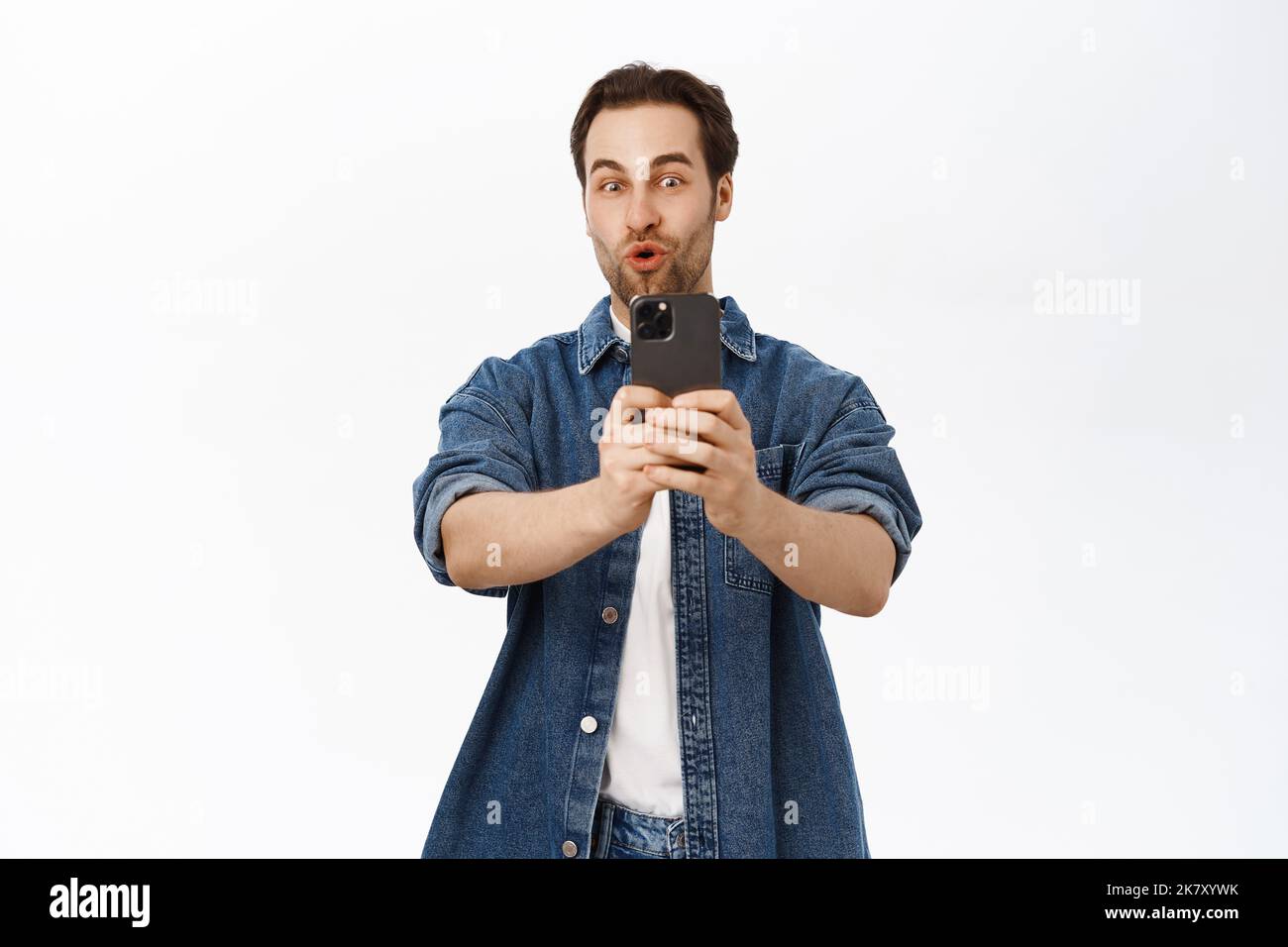 Happy smiling man takes photos or records video on his mobile phone ...