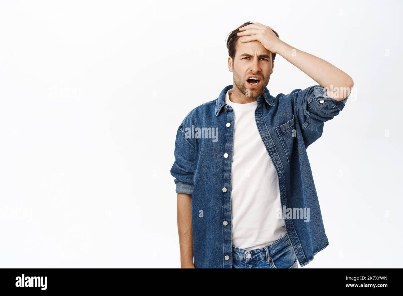 Upset young man slaps his forehead and looks devestated, frustrated by ...