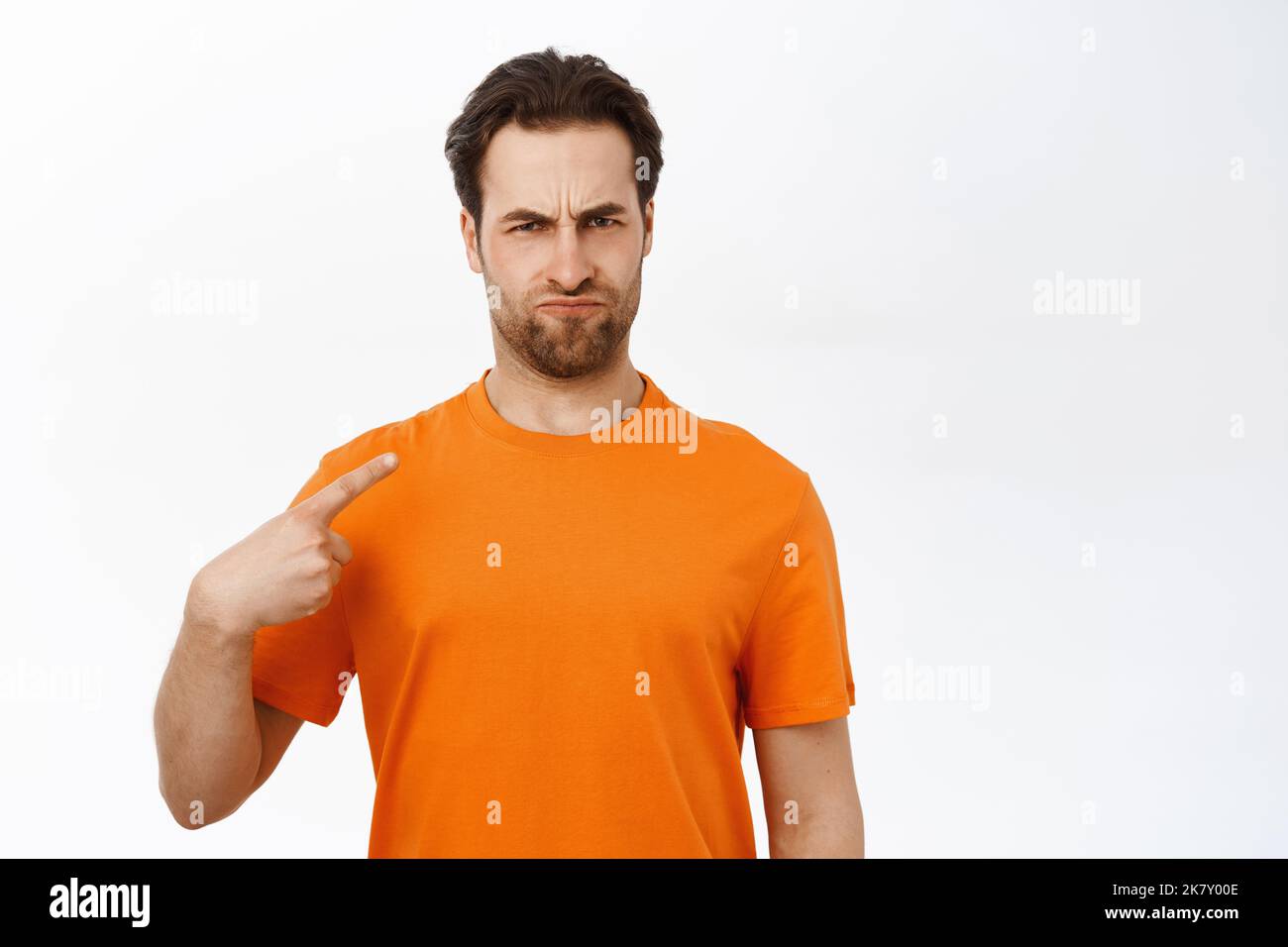 Portrait of man with angry face pointing at himself, looking grumpy ...