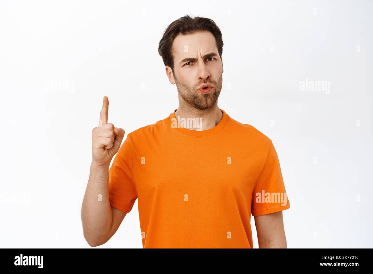 Portrait of disappointed guy pointing finger up, grimacing, being upset ...