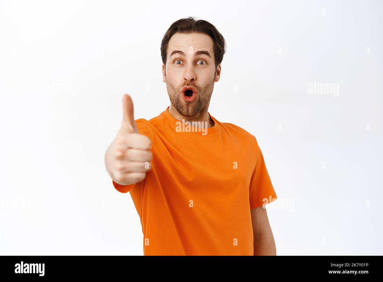 Man with impressed face shows thumbs up, recommends smth awesome ...