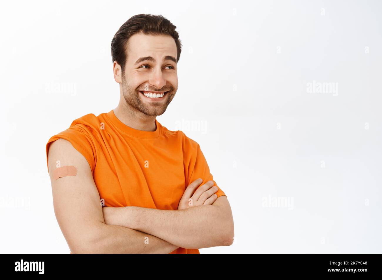 Handsome healthy guy smiles, shows shoulder with band aid after covid ...