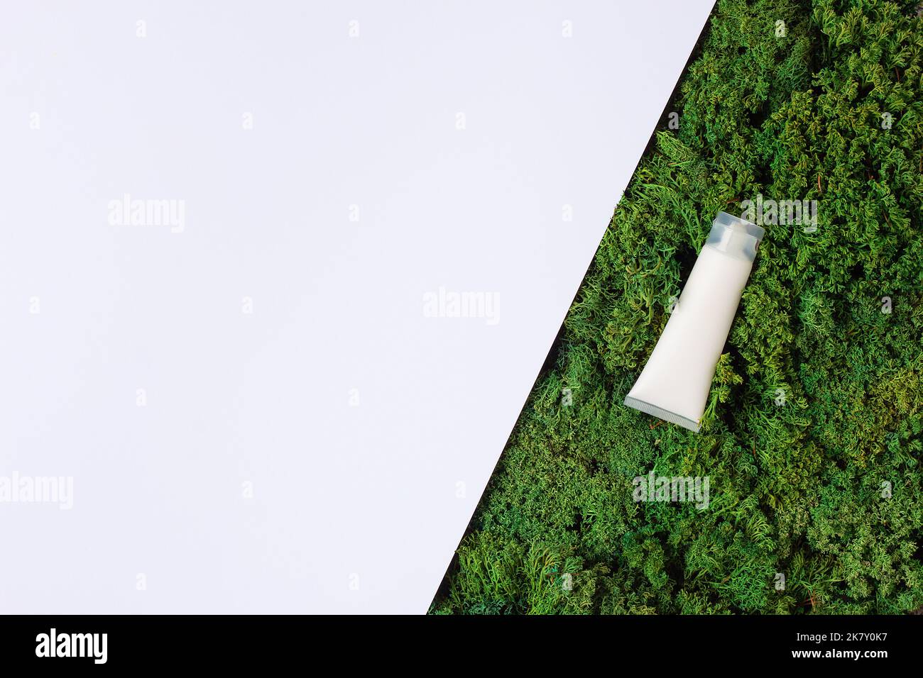 White tube of cosmetic cream with moss on white background. Flat lay ...