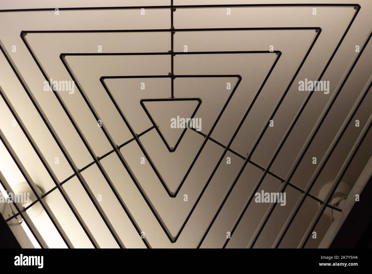 Triangular lamp in interior. Design of lighting device. Lamp on ceiling ...