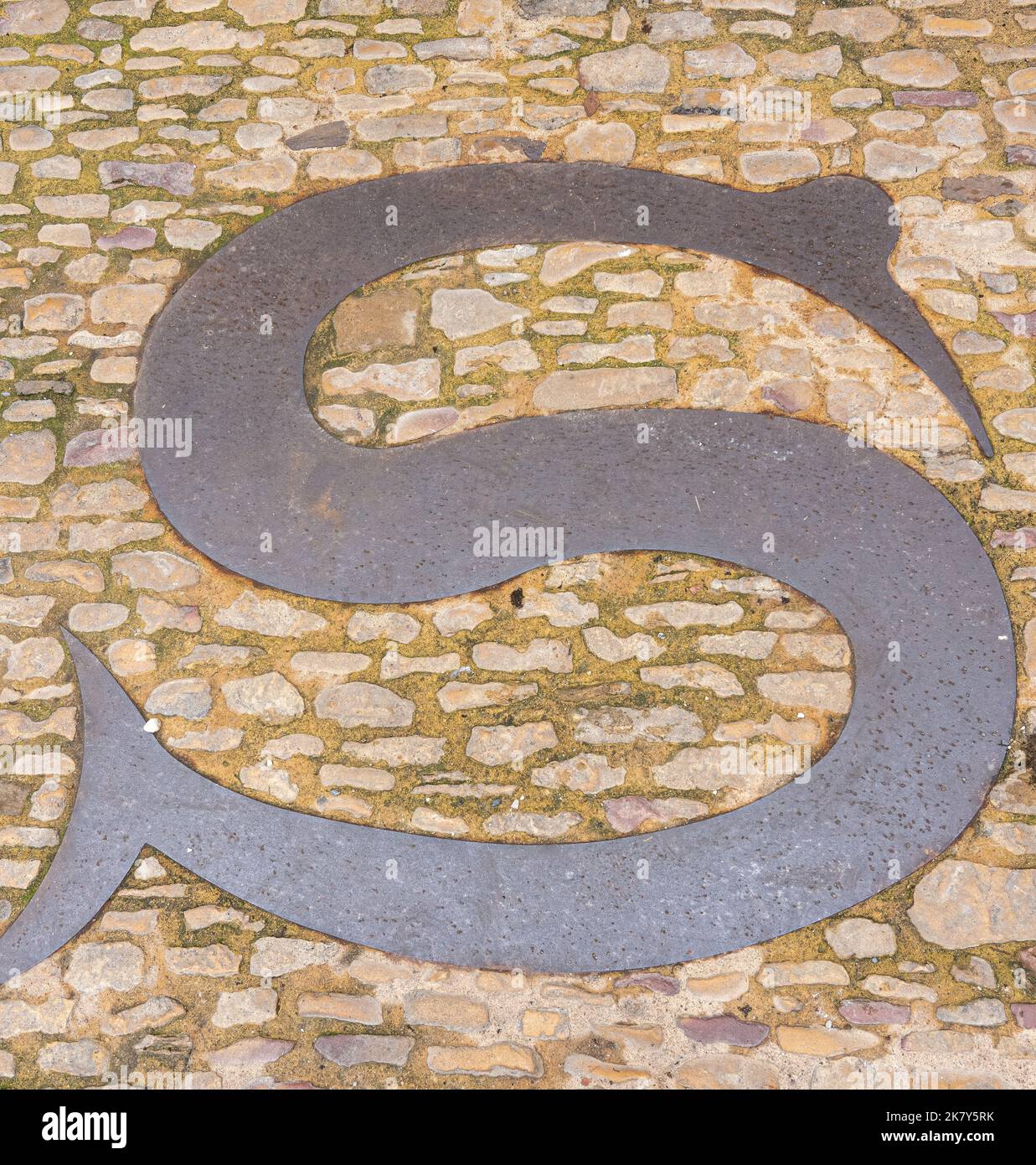 a stylized brass plaque symbol S in a stone pathway, logo of Sarlat-le ...