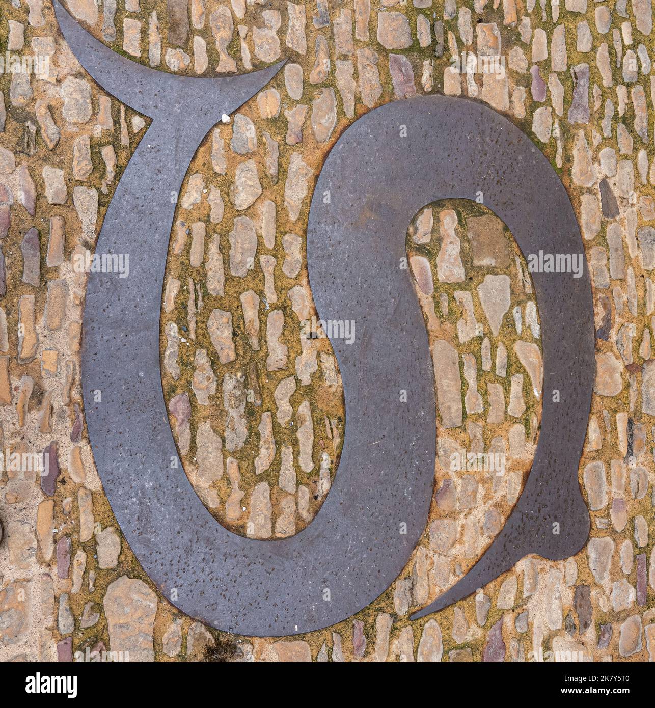 a stylized brass plaque symbol S in a stone pathway, logo of Sarlat-le ...
