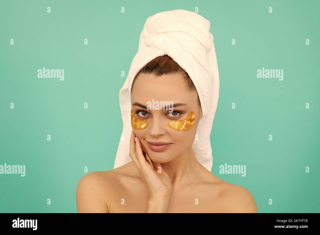 young woman has collagen golden eye patches on face smile with towel ...