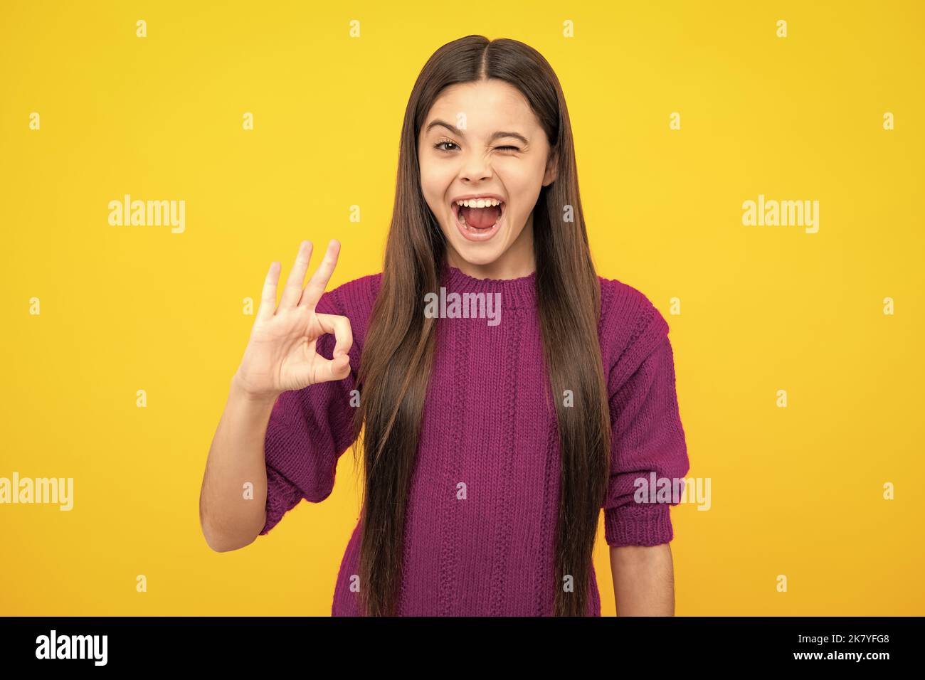 Okay. Beautiful child girl making ok sign and winking on yellow ...