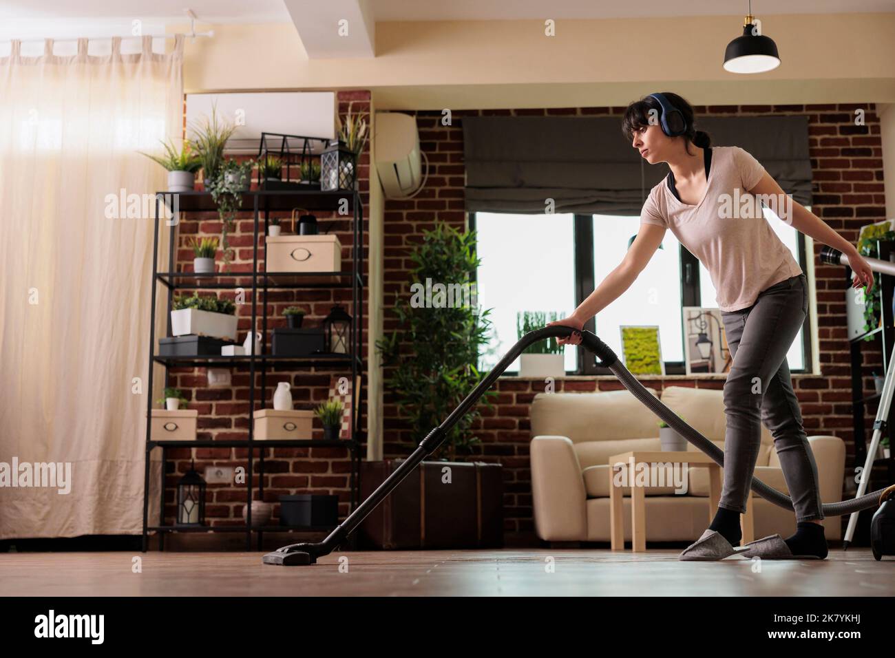 Woman with headphones listening to music doing housework with a modern ...