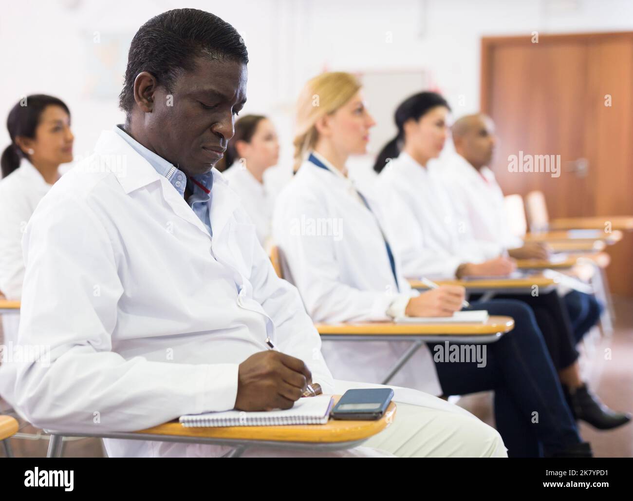 African american man in white coat taking notes during lecture Stock ...