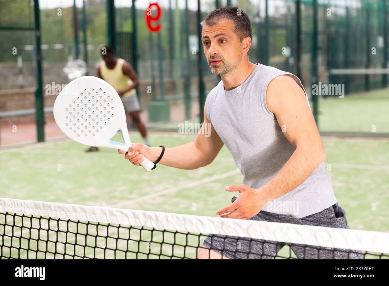 Athletic mens plays padel. View through tennis net Stock Photo - Alamy