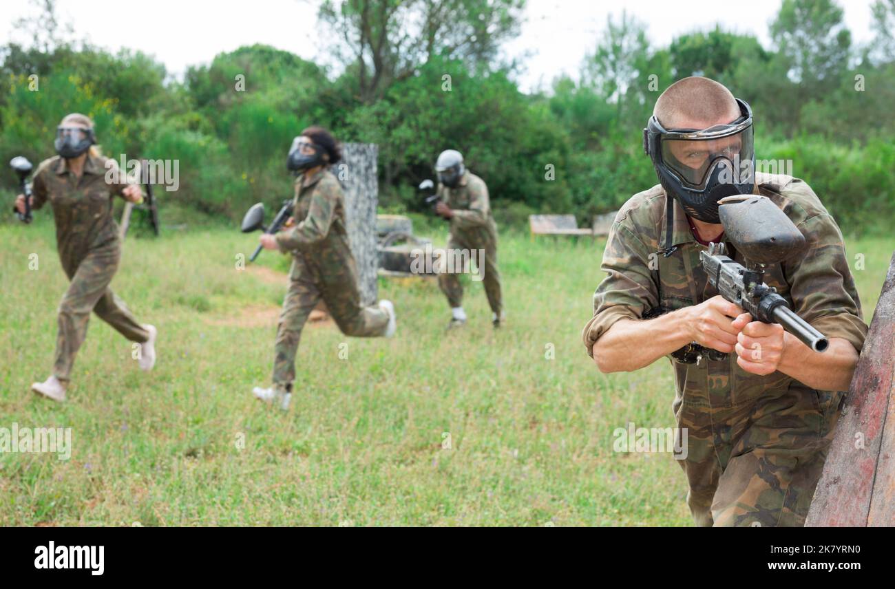 Portrait of man with gun in camouflage on paintball field Stock Photo ...