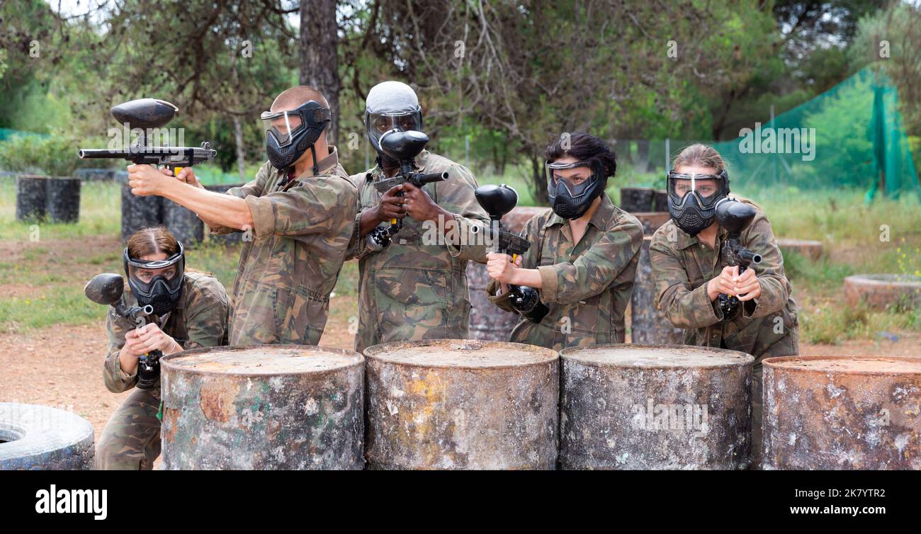Group of paintball players aiming and shooting with guns Stock Photo ...