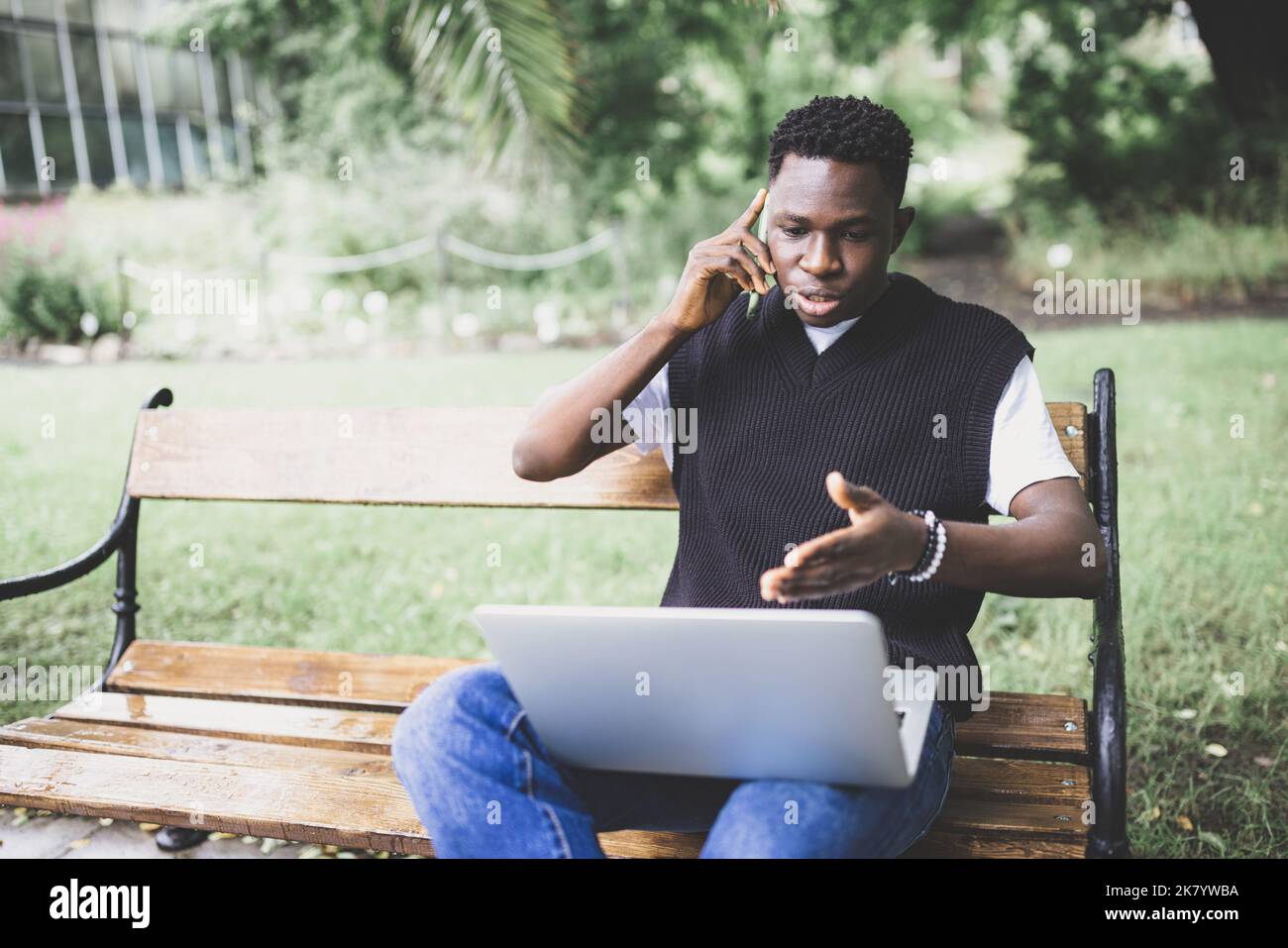 Young African man talking on phone disputing over computer, stressed ...