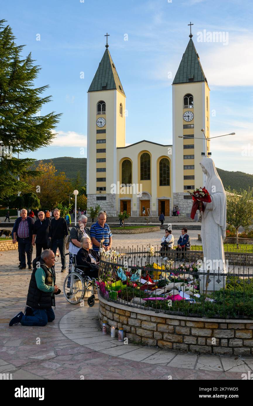 People praying around the statue of the Queen of Peace near the St ...