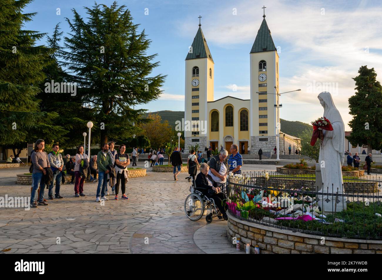 People praying around the statue of the Queen of Peace near the St ...