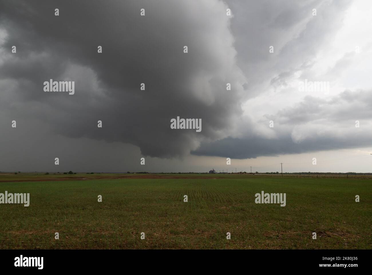 Thick, gray storm clouds hanging over an agricultural field with a ...