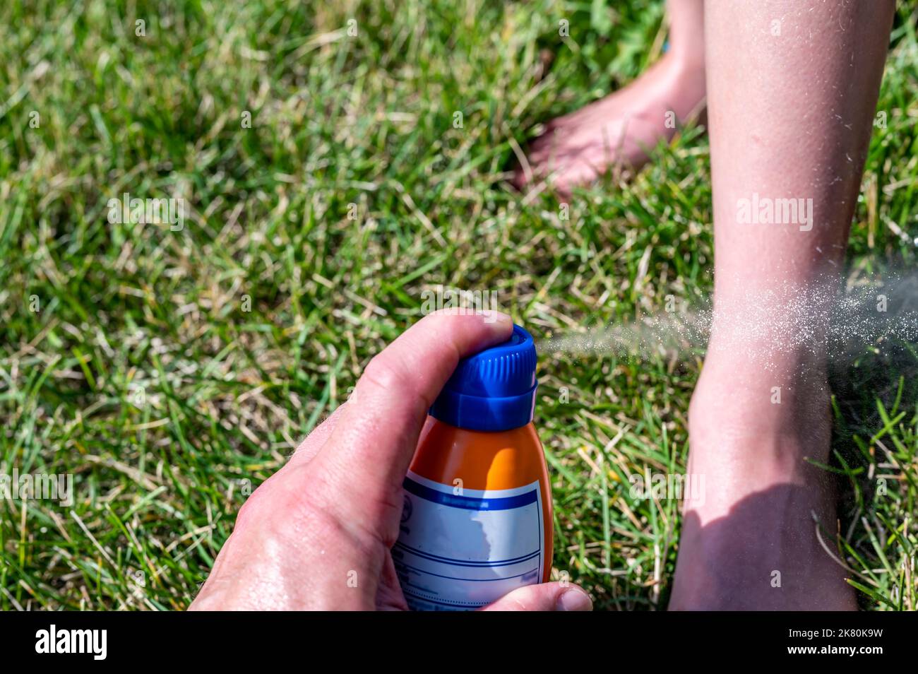 Applying an aerosol spray sunscreen to a young child in the summer ...