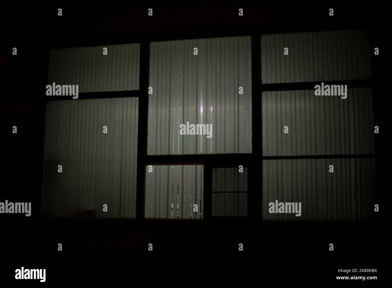 Big window at night. Window in building. Blinds cover light of lamp ...