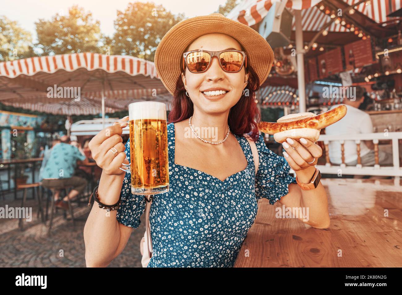 Happy girl drinking beer and eating traditional german bratwurst ...
