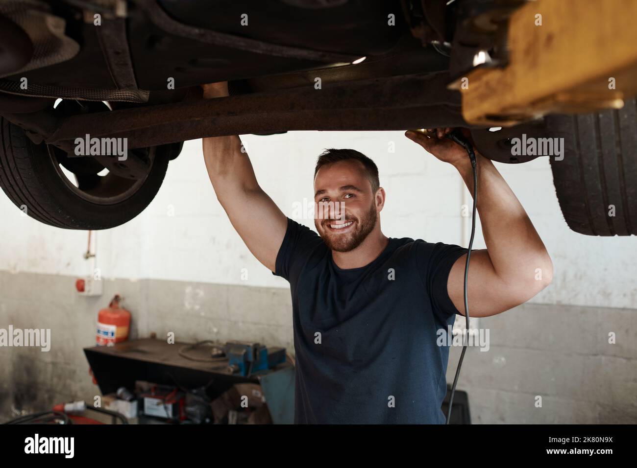 I do it with a smile on my face. a mechanic working under a lifted car ...