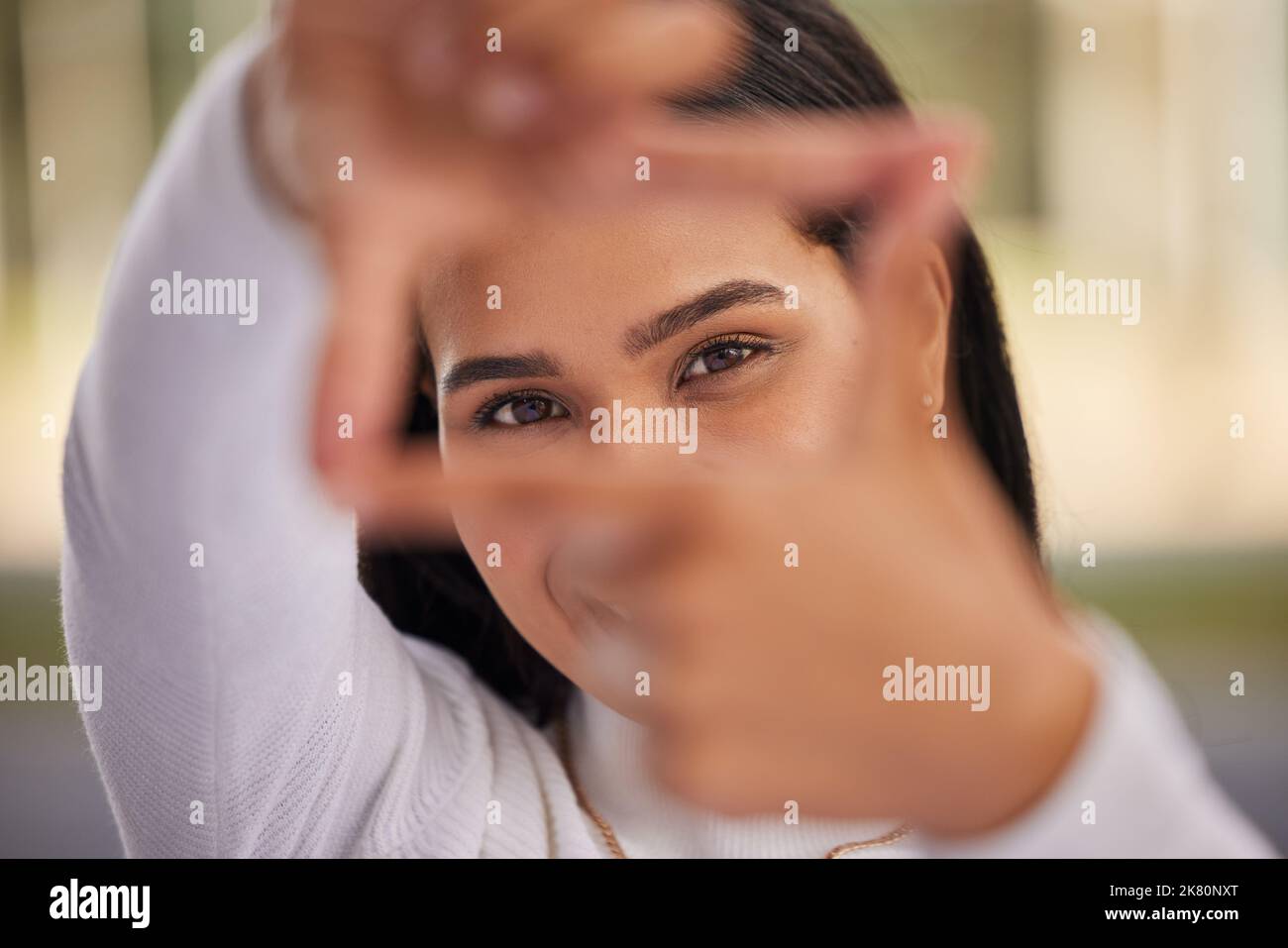 Hands, frame and eyes with a woman looking through her fingers while ...
