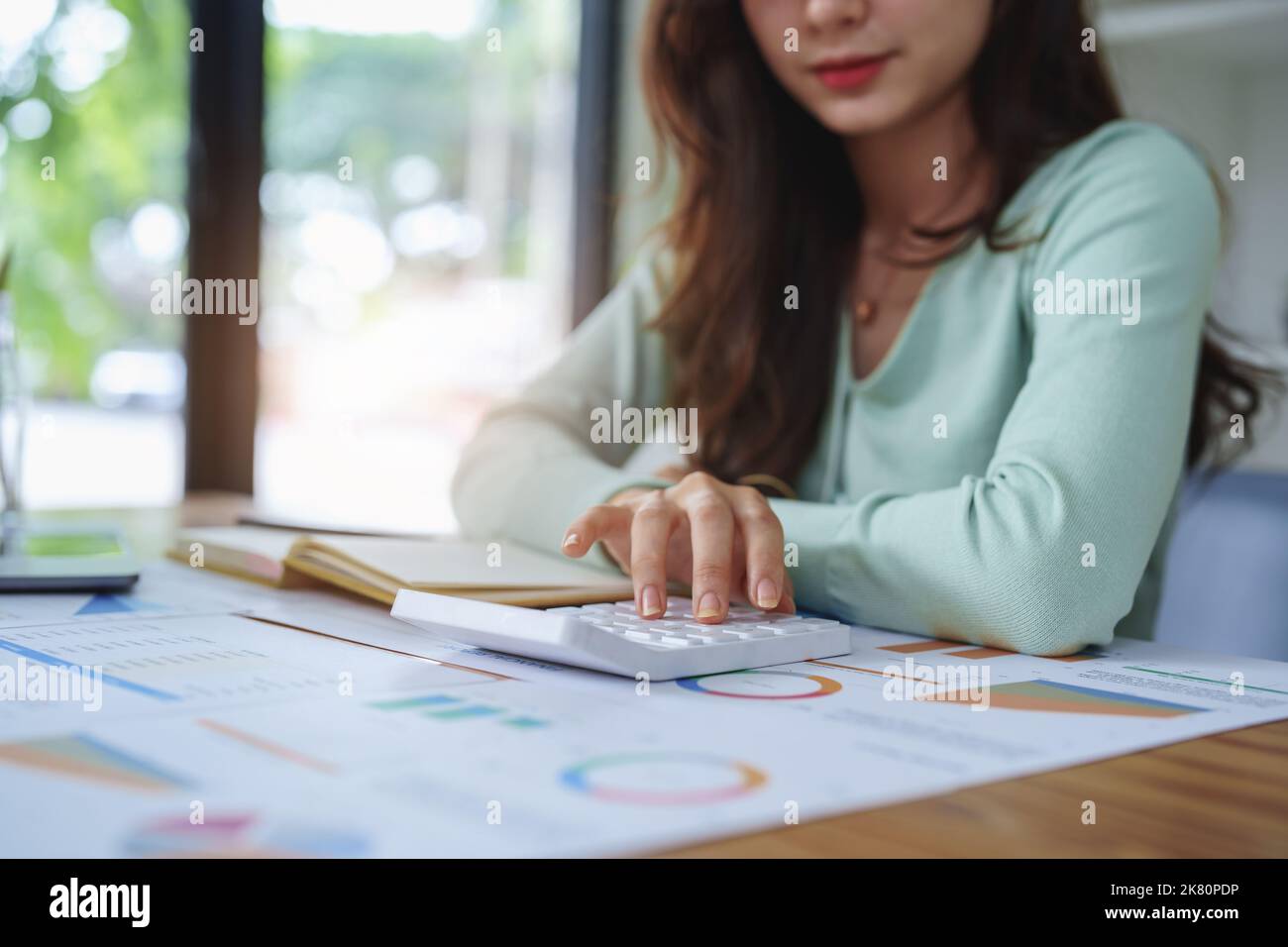 female employee using a calculator to calculate financial documents ...