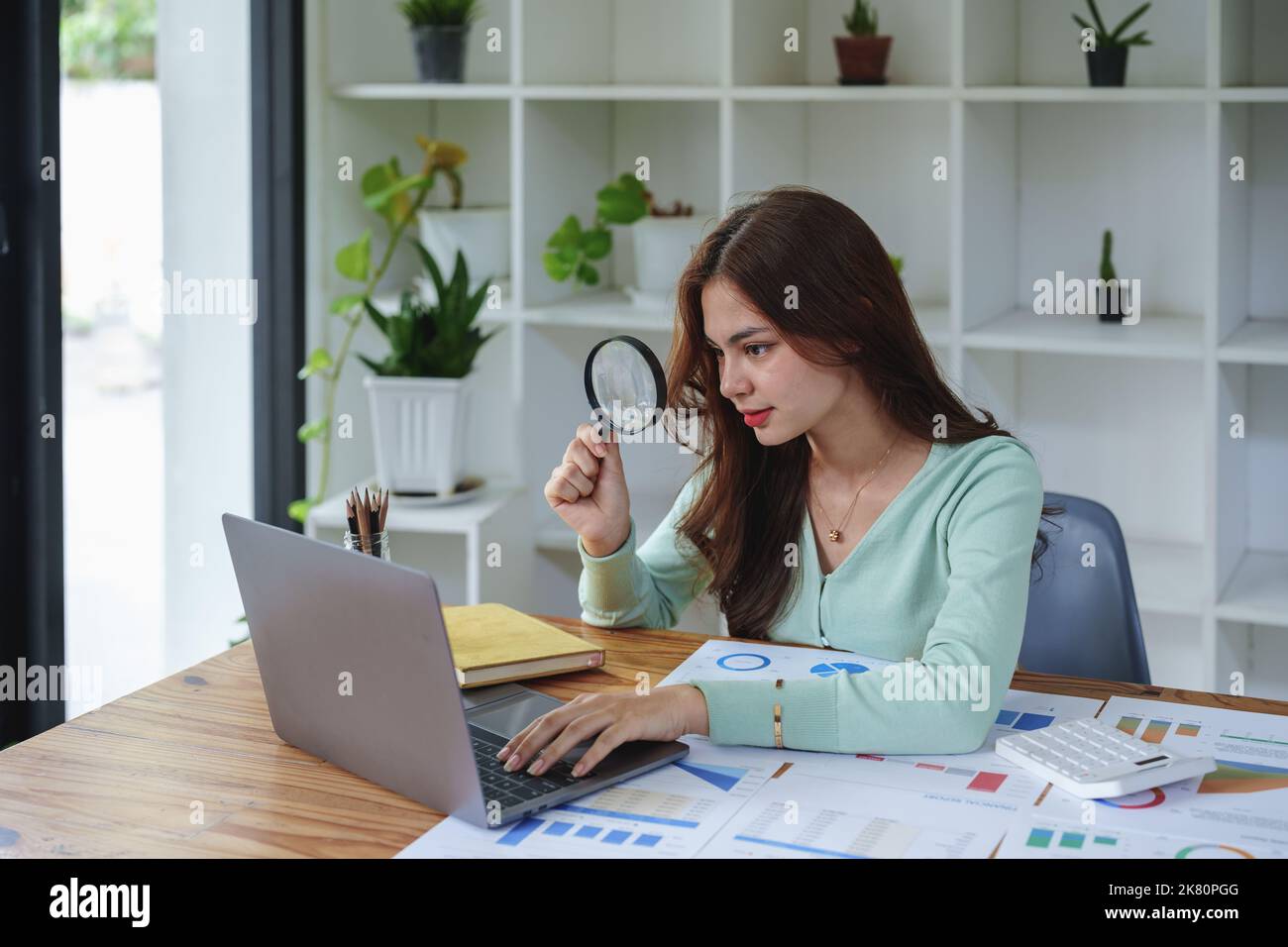 accountant holding a magnifying glass and using a calculator to check ...
