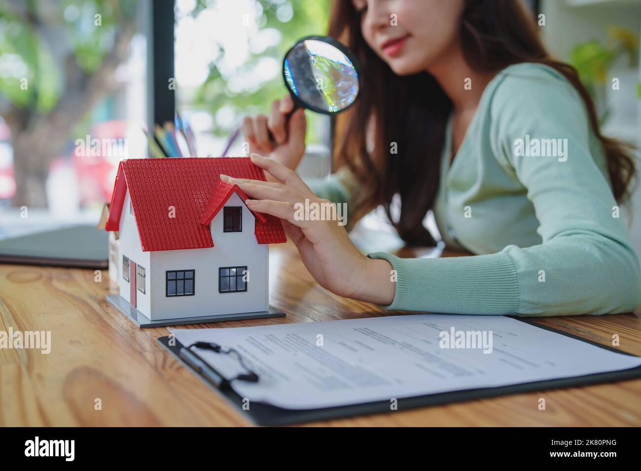 customer holding a magnifying glass to look at a house model inspection Stock Photo - Alamy