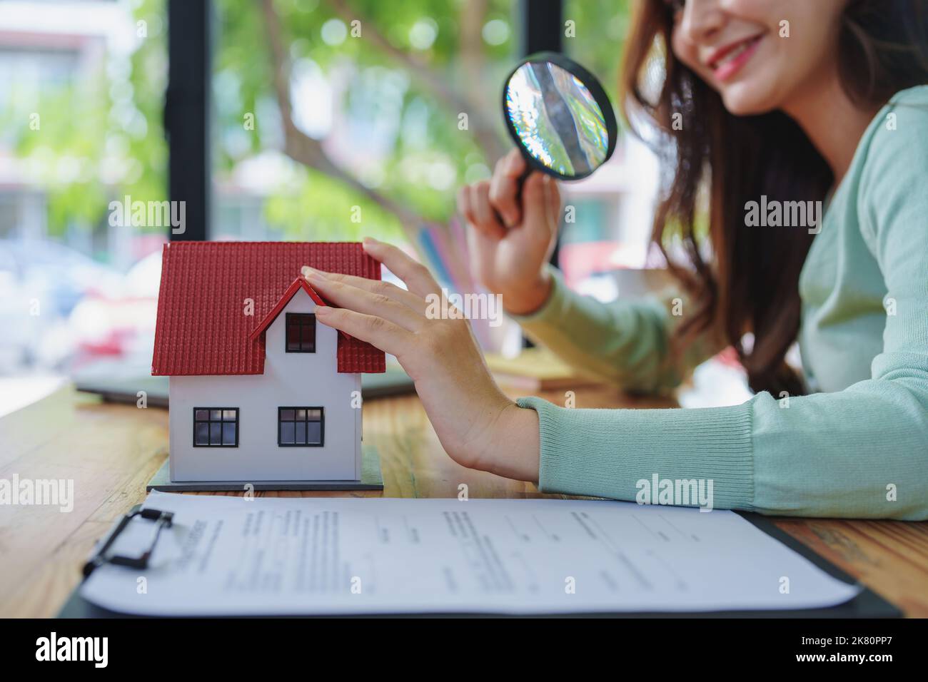 customer holding a magnifying glass to look at a house model inspection Stock Photo - Alamy