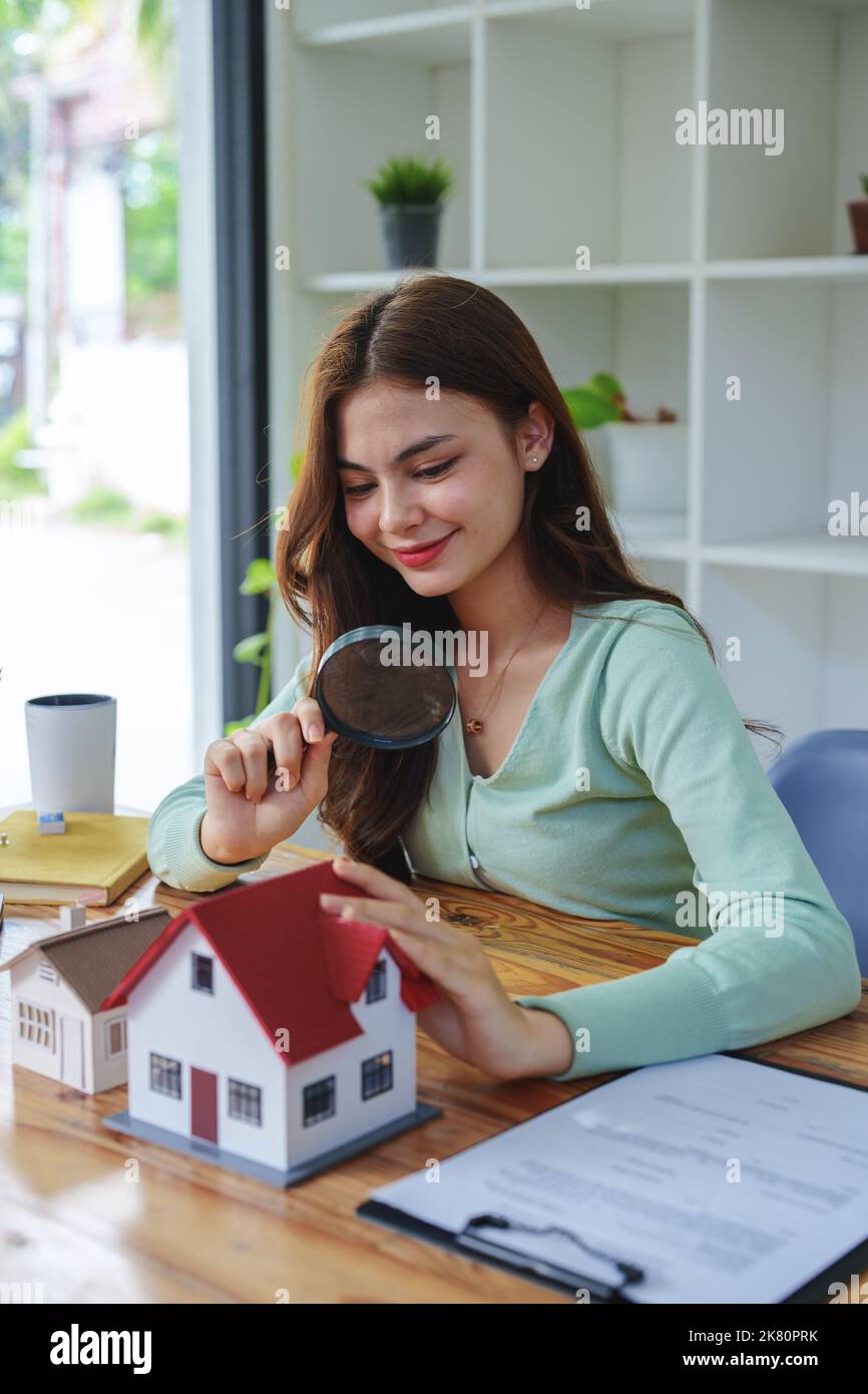 Customer holding a magnifying glass to select a house model, residential inspection concept ...