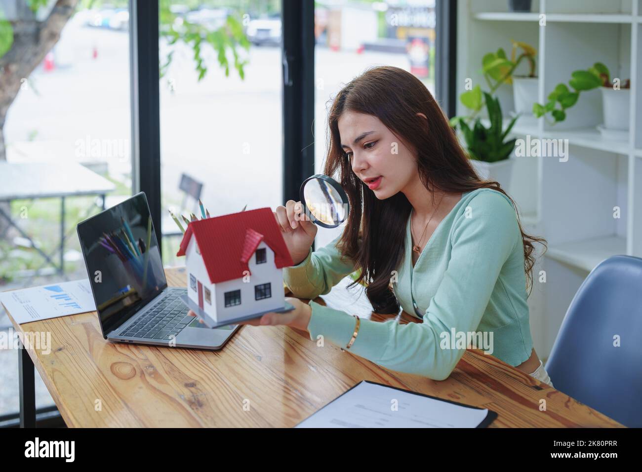 customer holding a magnifying glass to look at a house model inspection Stock Photo - Alamy