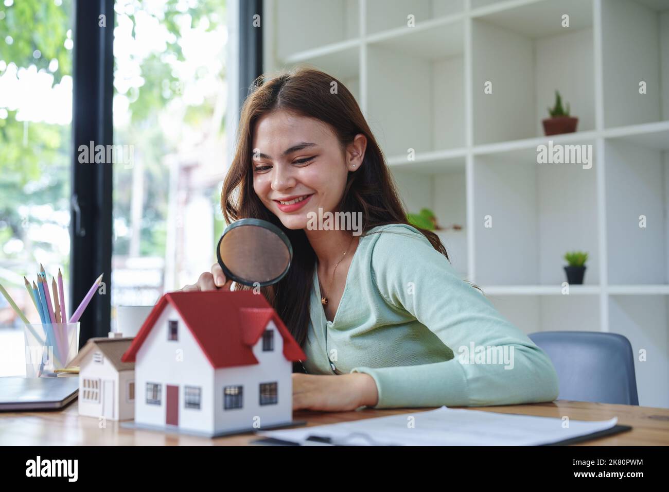 Customer holding a magnifying glass to select a house model, residential inspection concept ...