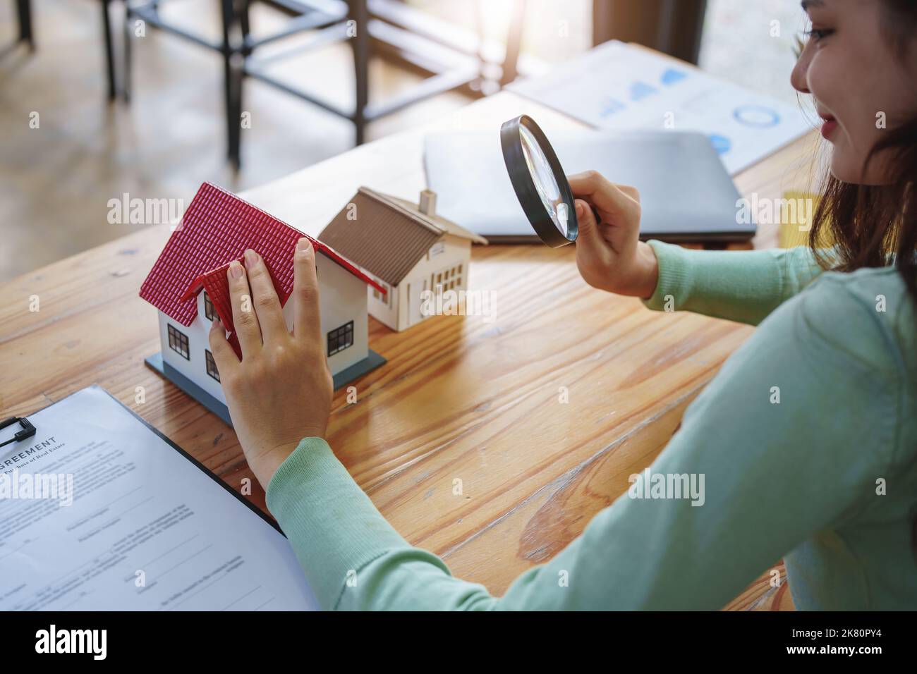 Customer holding a magnifying glass to select a house model, residential inspection concept ...